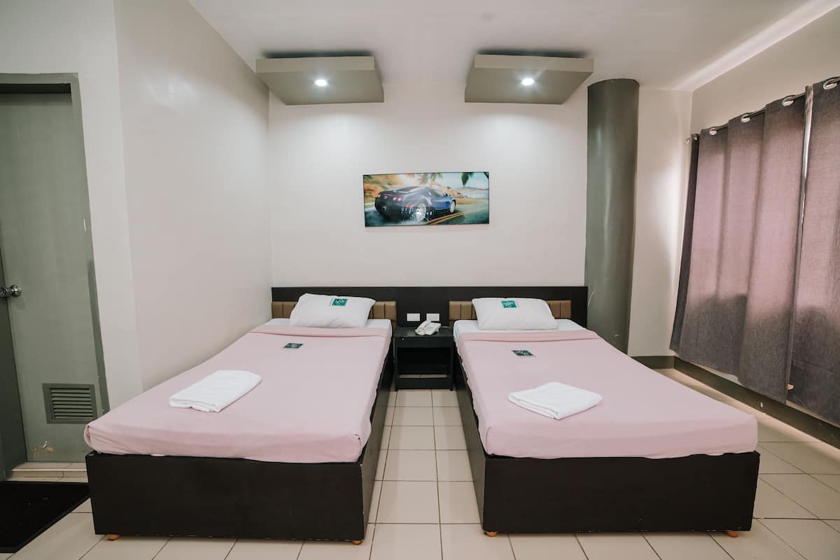 Quarto de hotel com duas camas de solteiro, um quadro na parede e um guarda-roupa.