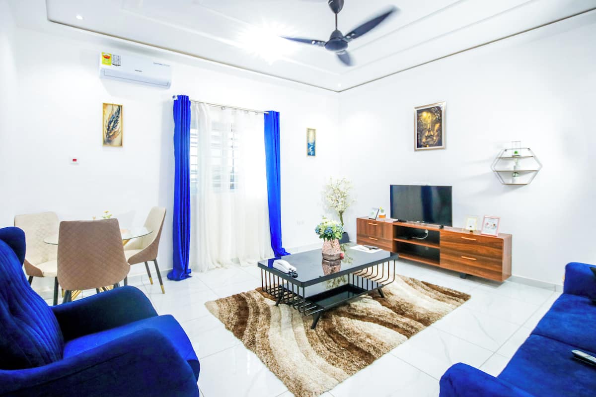 Uma sala de estar moderna com sofá, mesa de centro, televisão e área de jantar com cadeiras e mesa.
