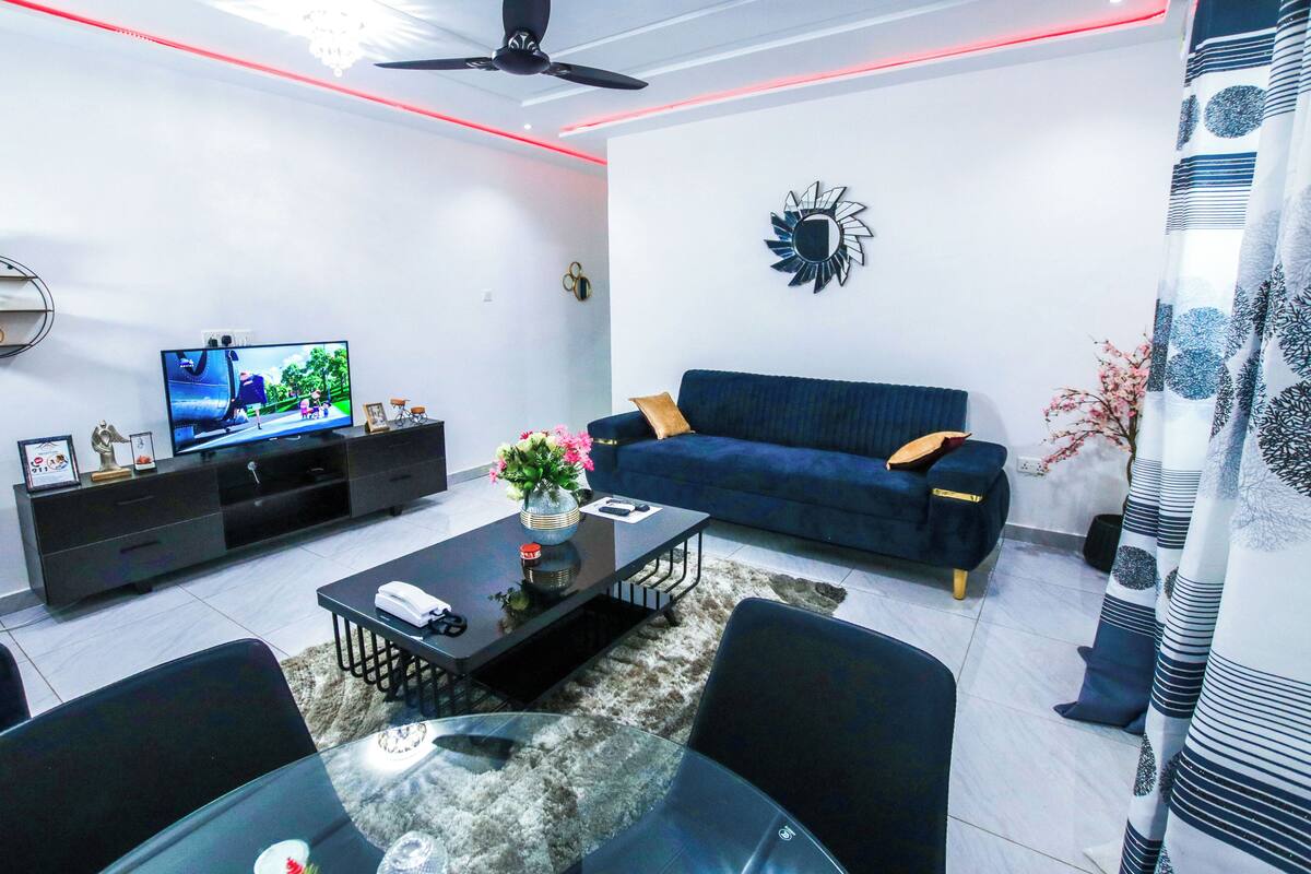 Uma sala de estar moderna com televisão, sofá, mesa de centro e cadeiras.