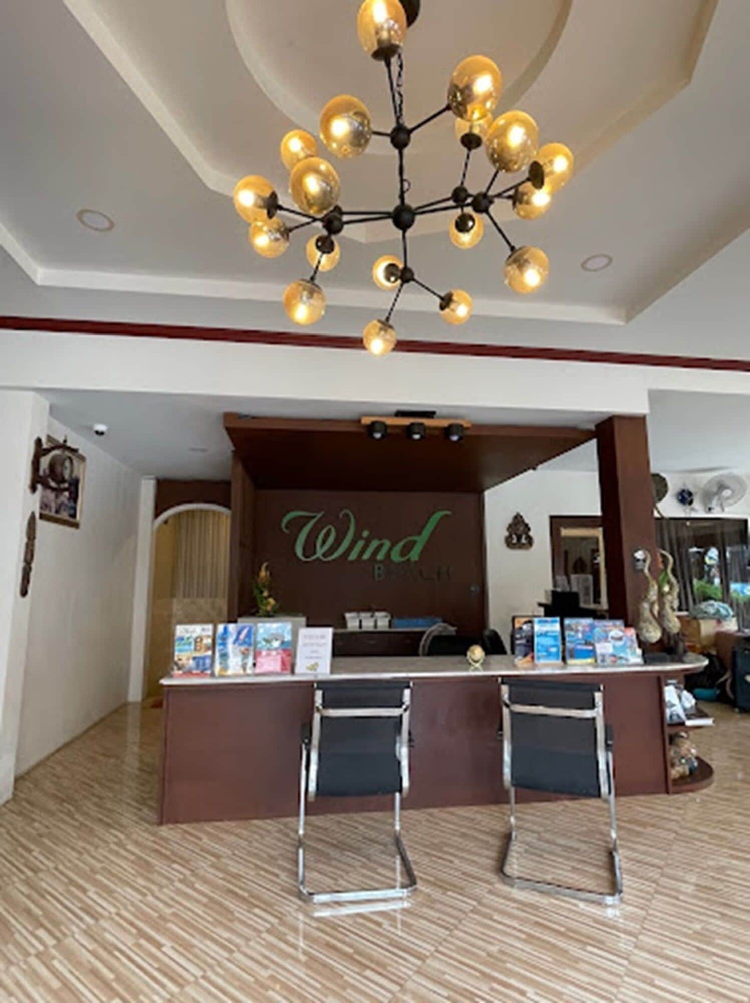 Uma área de recepção com um lustre, um balcão e uma placa com a inscrição 'Wind Beach'.