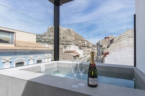 Varanda com uma garrafa de champanhe Moët & Chandon e dois copos, com vista para uma paisagem montanhosa com edifícios.