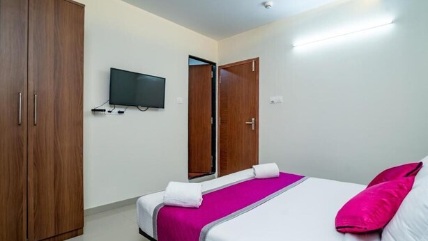 Quarto de hotel com cama, televisão e guarda-roupa.