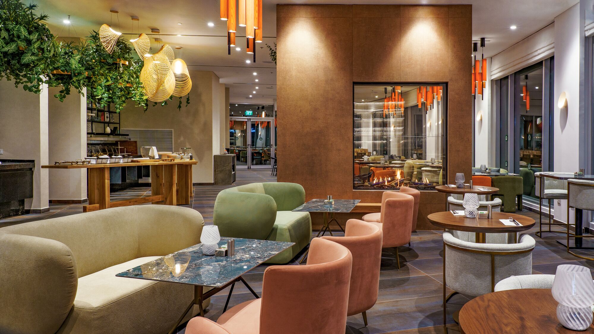 Interior de restaurante moderno com assentos confortáveis, uma lareira central e vista para a área de refeições.