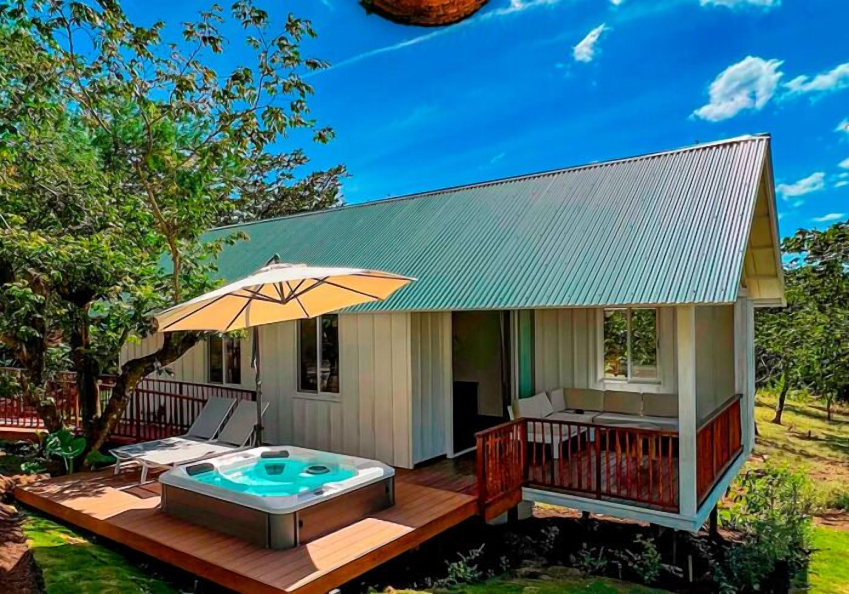 Uma casa de dois andares com hidromassagem no deck, um alpendre coberto e uma área de deck cercada.