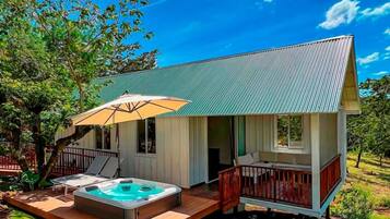 Uma casa de dois andares com hidromassagem no deck, um alpendre coberto e uma área de deck cercada.