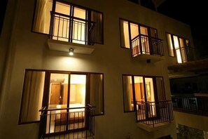 Um edifício de vários andares com varandas, janelas amplas e uma luz interior acolhedora.