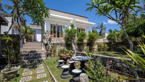 Uma casa moderna com escadaria de pedra que leva a um alpendre, cercada por vegetação exuberante e gramado padronizado.