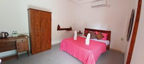 Quarto com duas camas, guarda-roupa de madeira, escrivaninha com chaleira e prateleira com uma planta.