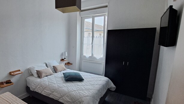 Quarto com cama, mesas de cabeceira, janela e guarda-roupa.