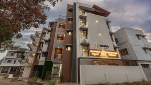 Um edifício moderno de vários andares com uma placa de 'treebo' bem visível, indicando um hotel ou resort.