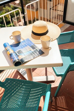 Uma mesa com uma revista, duas xícaras de café e um chapéu de palha.