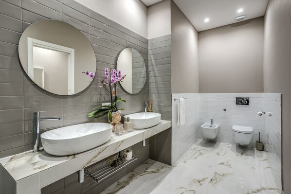 Uma casa de banho moderna com duas pias, um bidé e uma sanita.