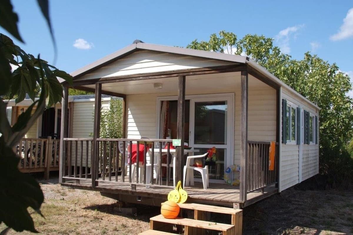 Uma casa móvel com varanda coberta, um pequeno deck e porta da frente.