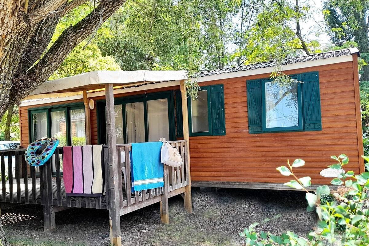 Uma cabana de madeira com varanda, um pequeno deck e uma janela com persianas.