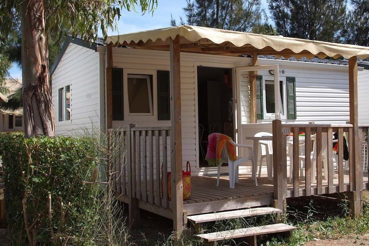 Uma casa móvel com varanda, deck de madeira e uma pequena mesa.