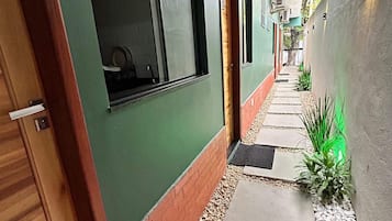 Um corredor estreito com parede verde, porta de madeira e uma janela.