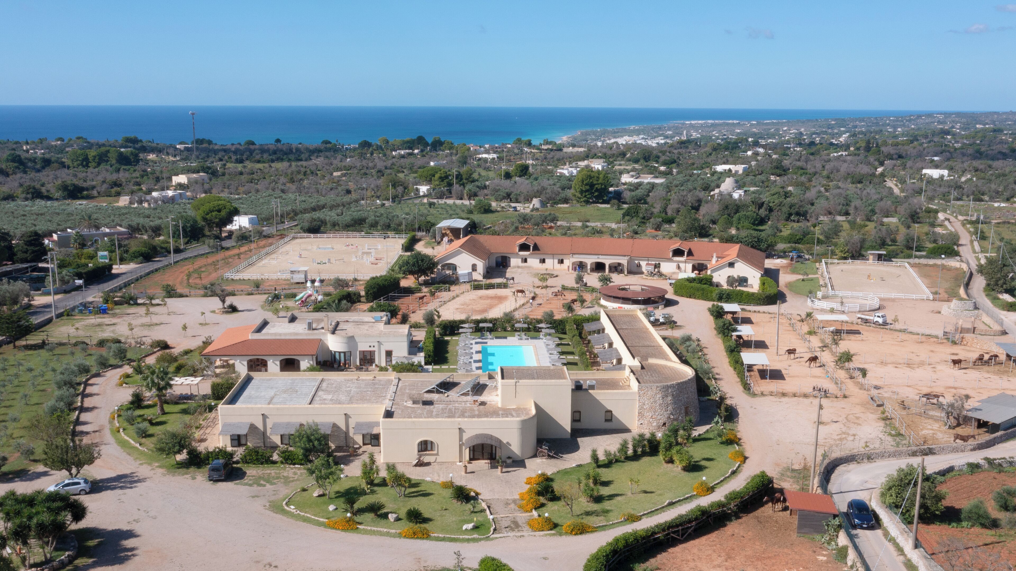 Vista aérea de um resort com vários edifícios, uma piscina e uma vasta área aberta.