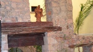 Um pátio com arcos de pedra, uma estátua e vasos com plantas.