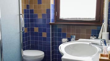 Casa de banho com sanita, lavatório e paredes azulejadas em azul.