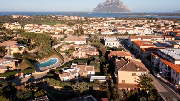 Um bairro residencial com casas, uma piscina e uma montanha ao fundo.