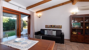Uma sala de estar acolhedora com uma mesa de jantar de madeira, um sofá preto e um aparador com portas de vidro.