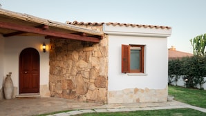 Uma casa com fachada de pedra, porta de madeira e janela com persianas.