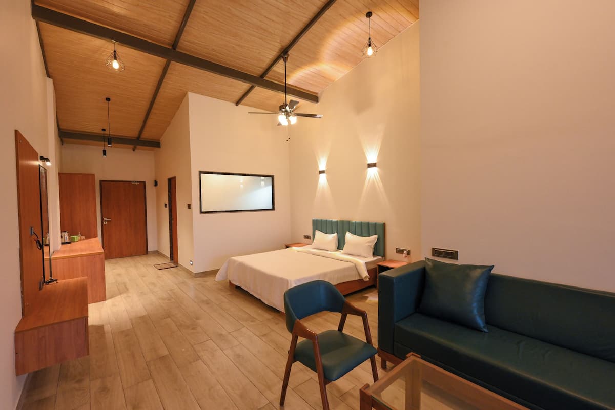 Quarto de hotel com cama, escrivaninha, cadeira, sofá e ventoinha no teto.