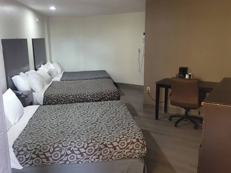 Quarto de hotel com duas camas, uma escrivaninha, uma cadeira e um guarda-roupa.