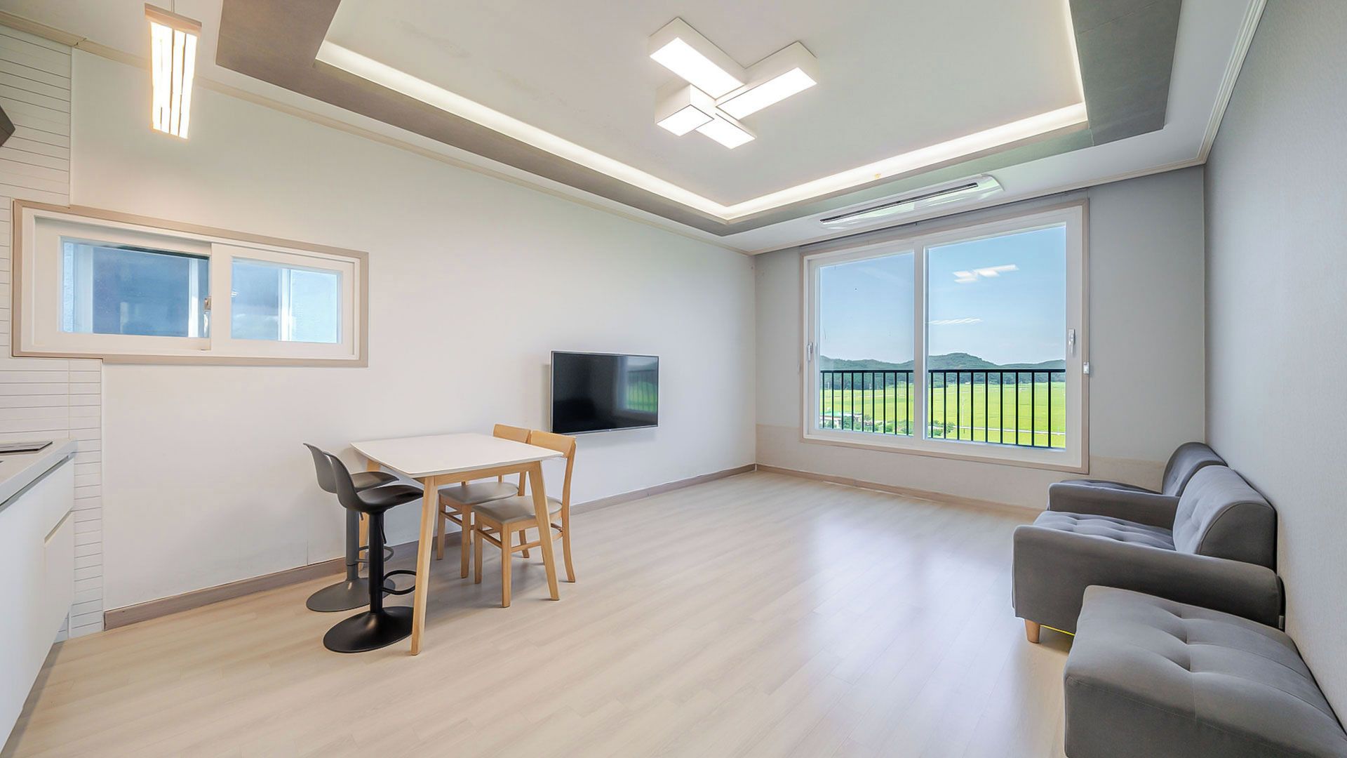 Sala moderna com área de jantar, televisão de tela plana e varanda com vista.