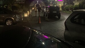 Vista noturna de um edifício com pilares iluminados e um arco central.