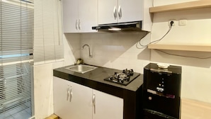 Cozinha compacta com armários brancos, bancada preta, fogão embutido e geladeira preta.