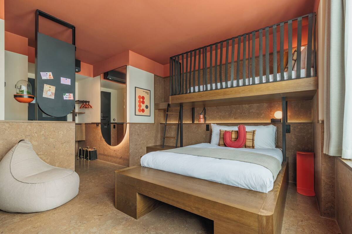 Quarto moderno com beliche, mesa de cabeceira, cadeira e espelho.