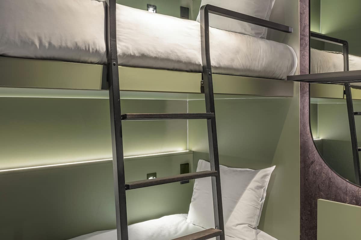 Quarto com beliche, escada, paredes verdes e chão de mármore.