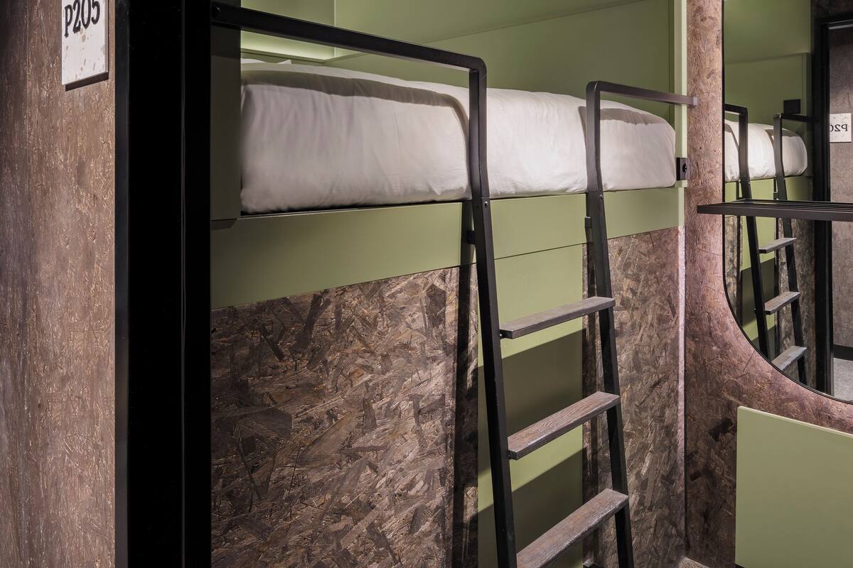 Quarto com beliche, parede de mármore, espelho e placa indicando o número do quarto P205.