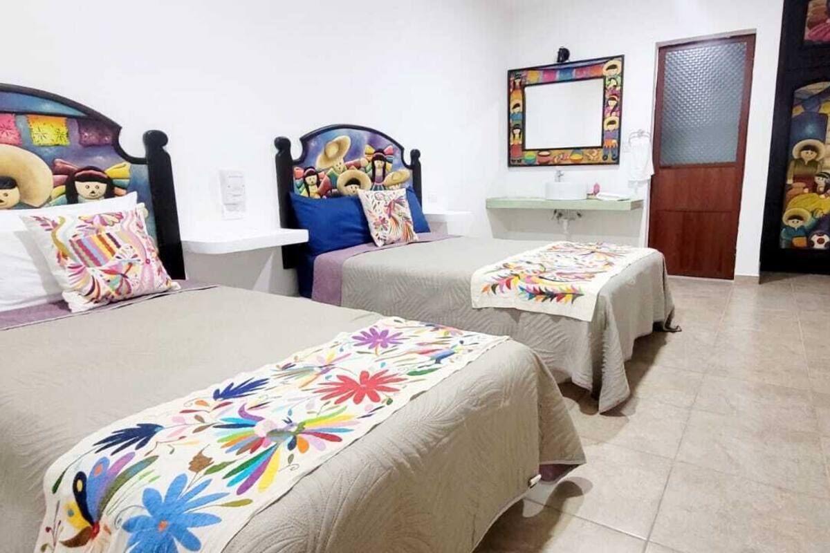 Quarto com duas camas, uma mesa pequena, um espelho e uma porta decorada.