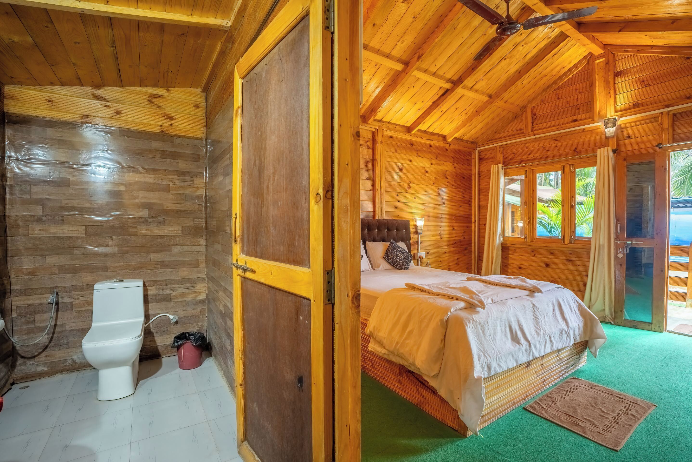 Uma cabana de madeira com banheiro, cama e vista para o exterior.