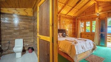 Uma cabana de madeira com banheiro, cama e vista para o exterior.