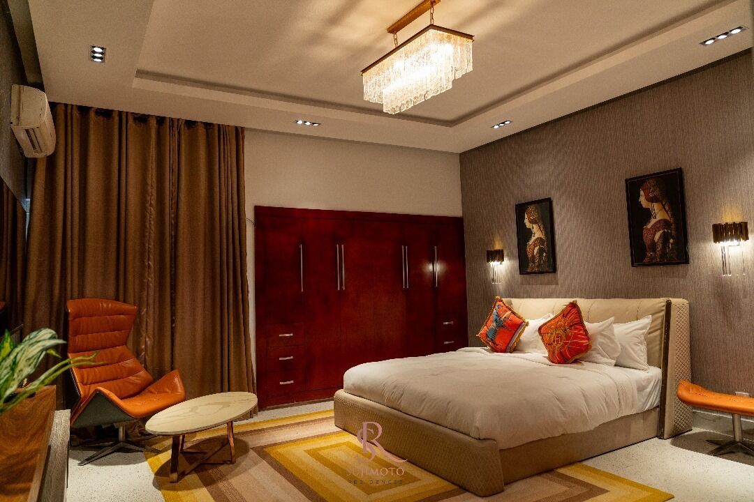 Quarto moderno com uma cama grande, um guarda-roupa de madeira, uma poltrona de couro e uma mesinha.