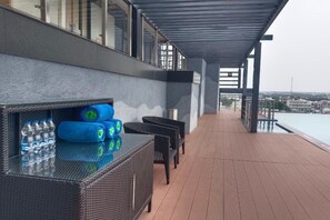 Área de estar externa com móveis de vime e vista para a piscina.