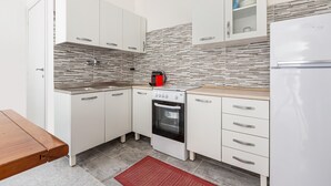 Uma cozinha compacta com armários brancos, forno embutido e geladeira.