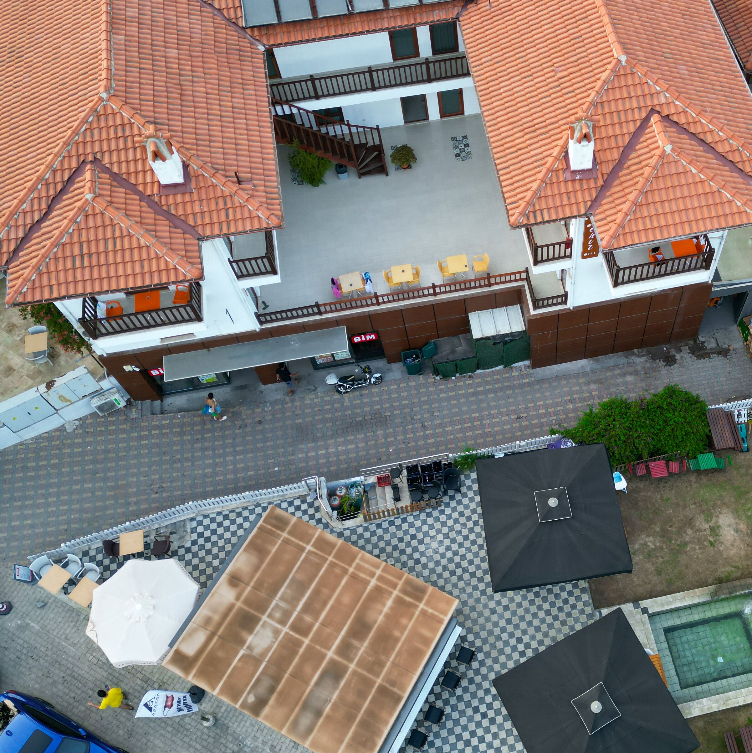 Um edifício de vários andares com telhado em telhas, área de estar ao ar livre e piscina.