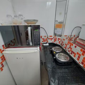 Cozinha compacta com geladeira, micro-ondas e fogão.