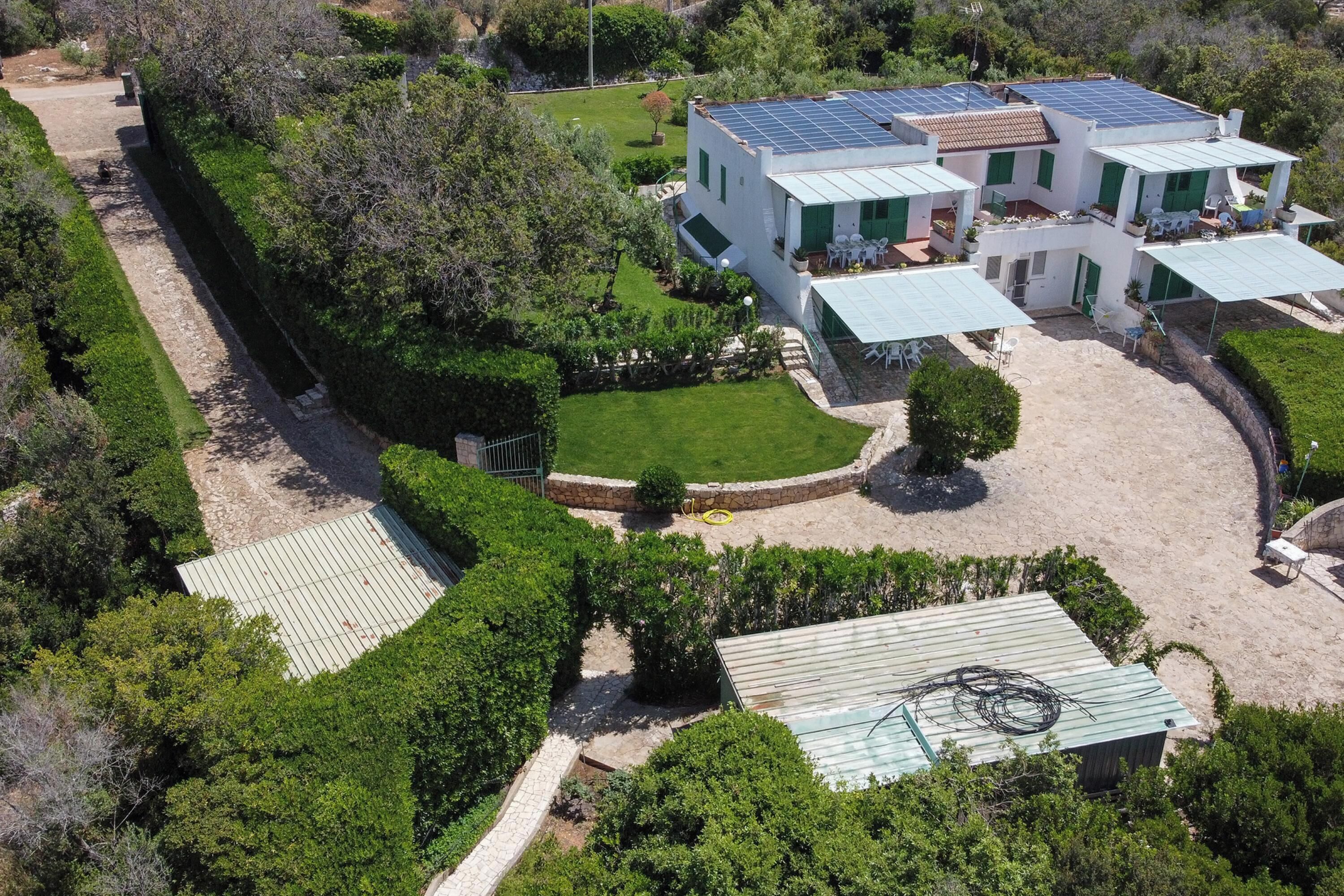 Uma casa moderna de dois andares com painéis solares, um jardim bem cuidado e uma piscina.