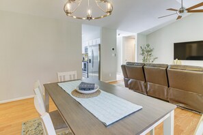 Uma sala de estar moderna com um sofá de couro marrom, uma mesa de jantar com um jogo americano e um ventilador de teto.