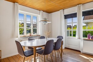 Uma sala de jantar com uma mesa redonda, seis cadeiras e um lustre.