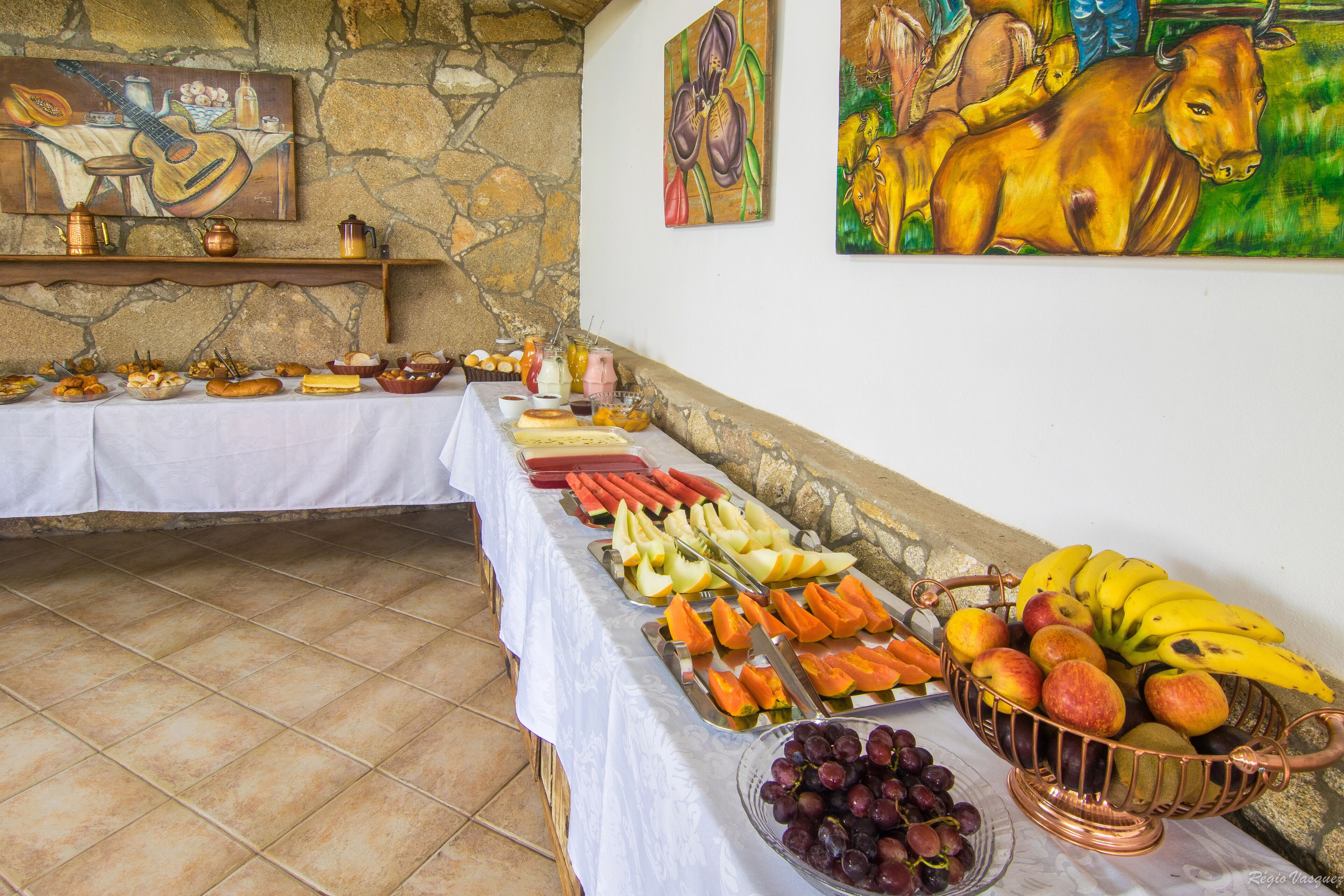 Uma mesa de buffet com frutas, legumes e pães variados.