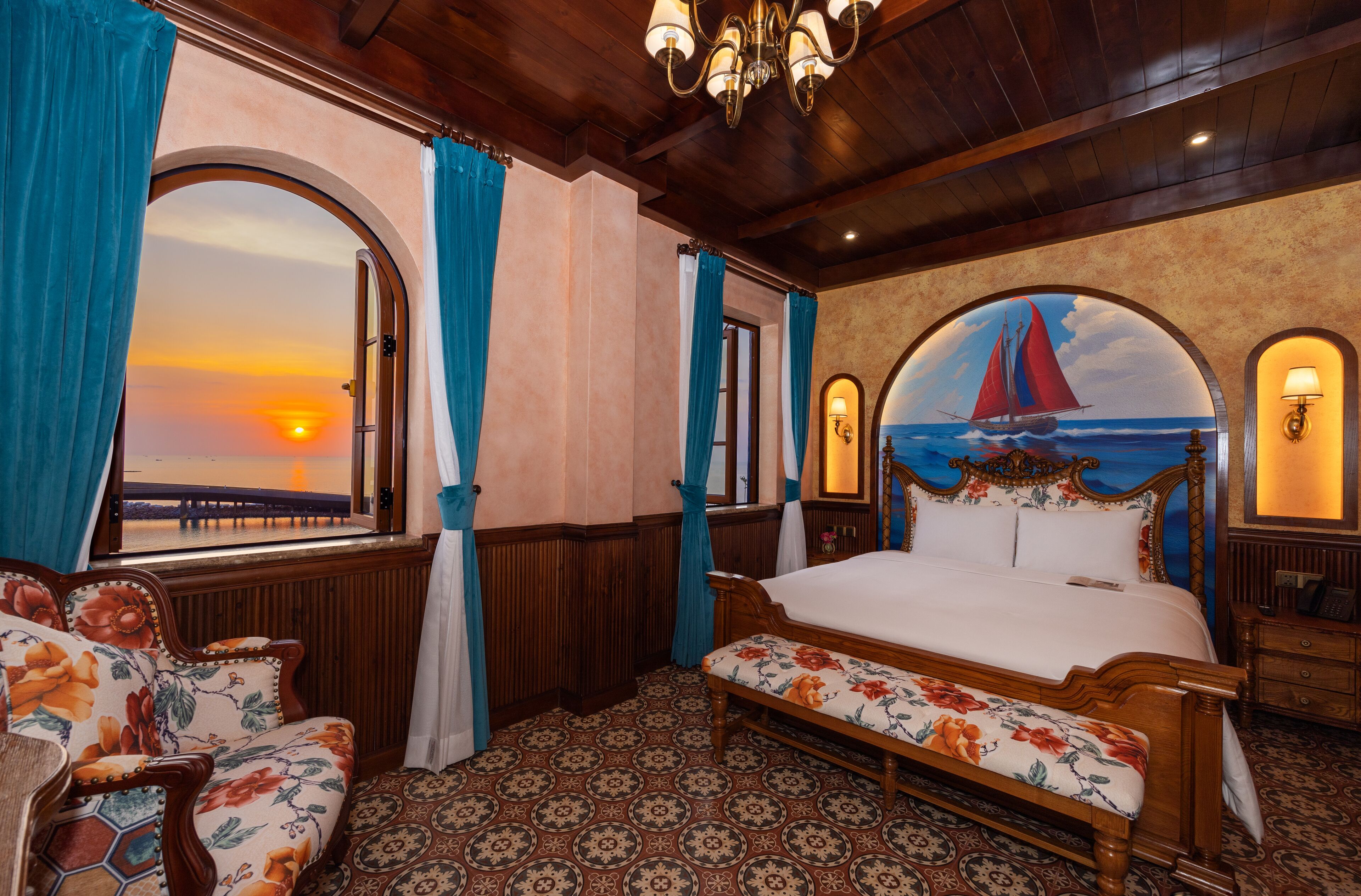 Quarto com uma janela grande, uma cama, um banquinho e um mural de parede com um veleiro.