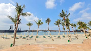 Na praia, areia branca, espreguiçadeiras, guarda-sóis