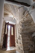 Interior em pedra com uma porta de madeira e vista para o exterior.