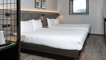 Quarto de hotel com duas camas, uma janela e vista para um edifício.